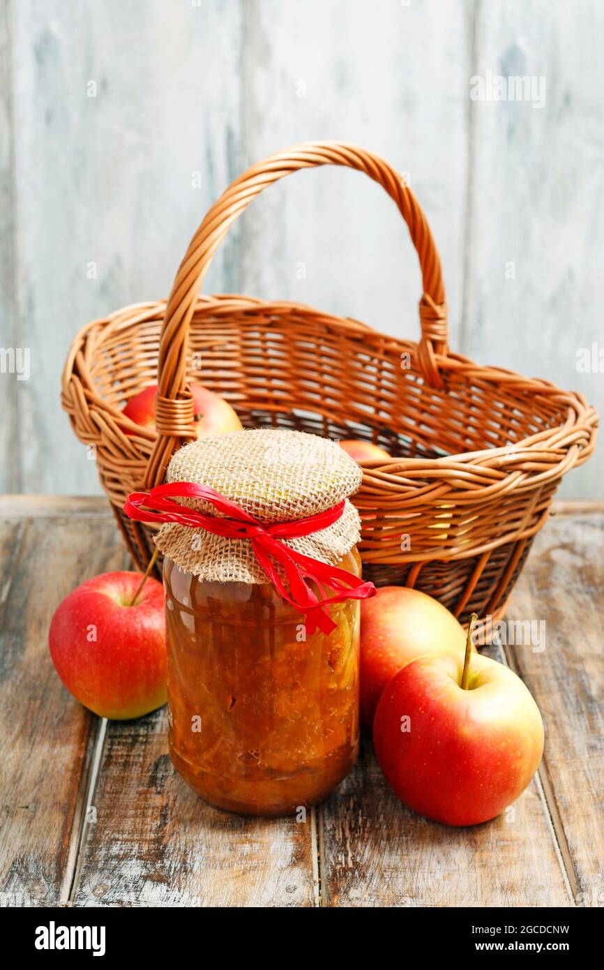 Jar with apple jam and wicker basket with raw fruits. Healthy food ...