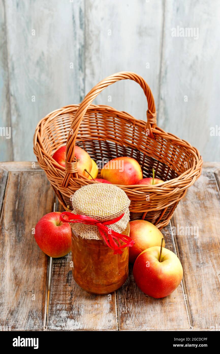 Jar with apple jam and wicker basket with raw fruits. Healthy food ...