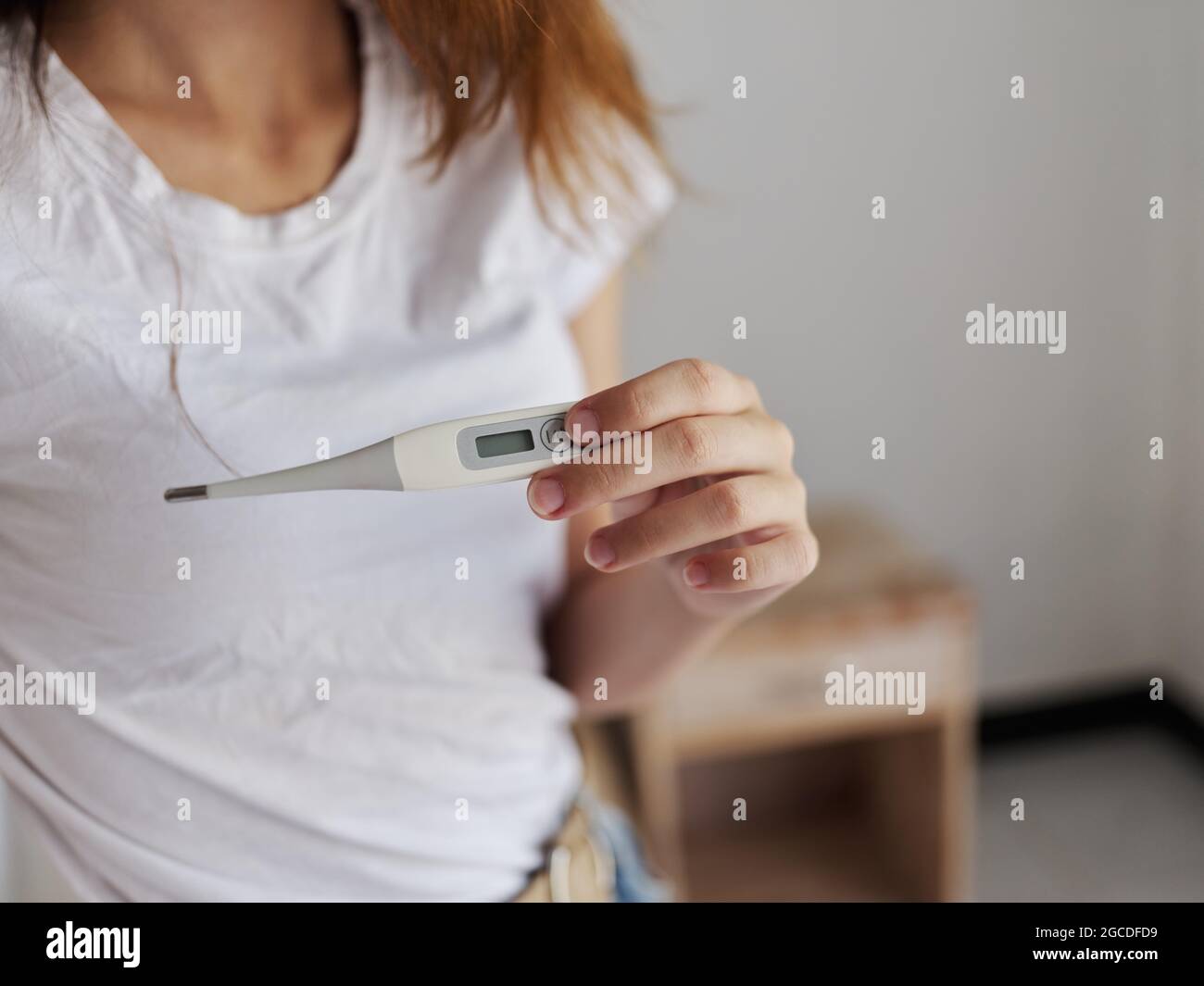 woman in white t-shirt holding thermometer temperature check Stock ...