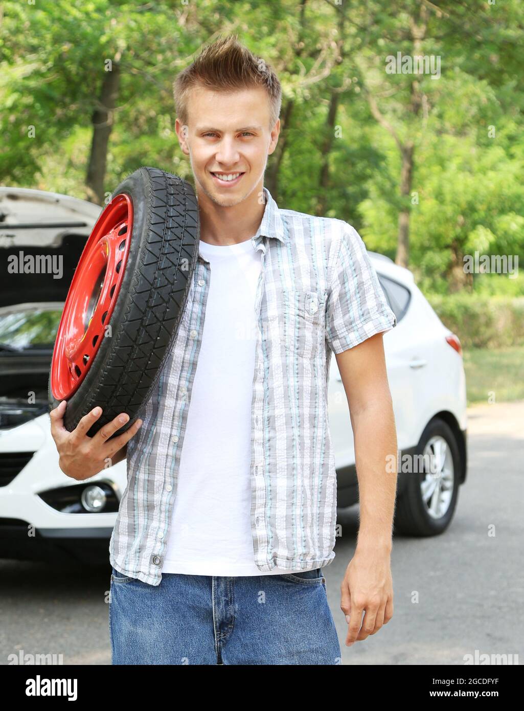 Man driver holding tire on shoulder Stock Photo - Alamy