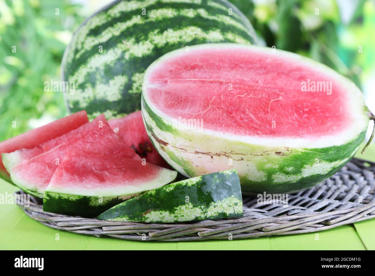 Ripe watermelons on wicker tray on wooden table on nature background ...