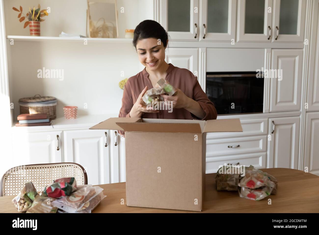 Smiling Indian woman unpack box with food delivery Stock Photo - Alamy