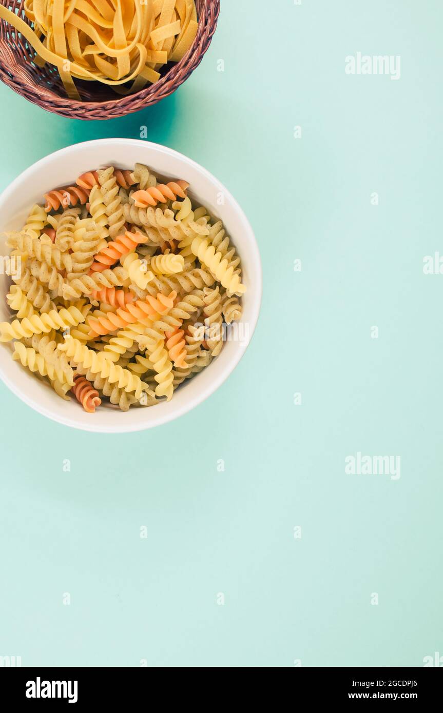 Plate with pasta twists and tagliatelle isolated on cyan background ...