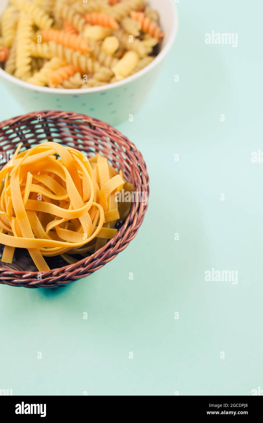 Plate with pasta twists and tagliatelle isolated on cyan background ...