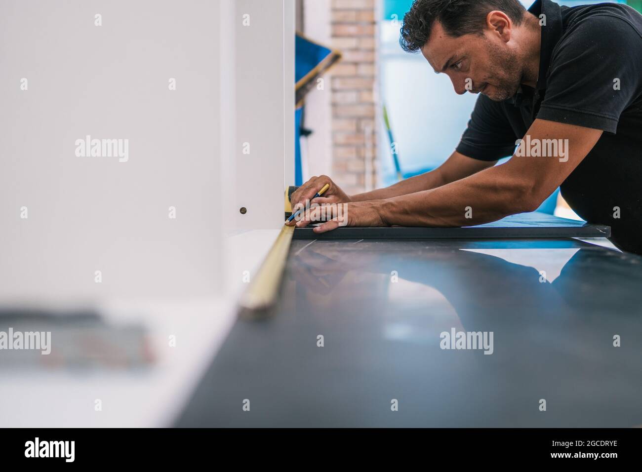 Man marking a surface with a pencil and ruler in a workshop Stock Photo ...