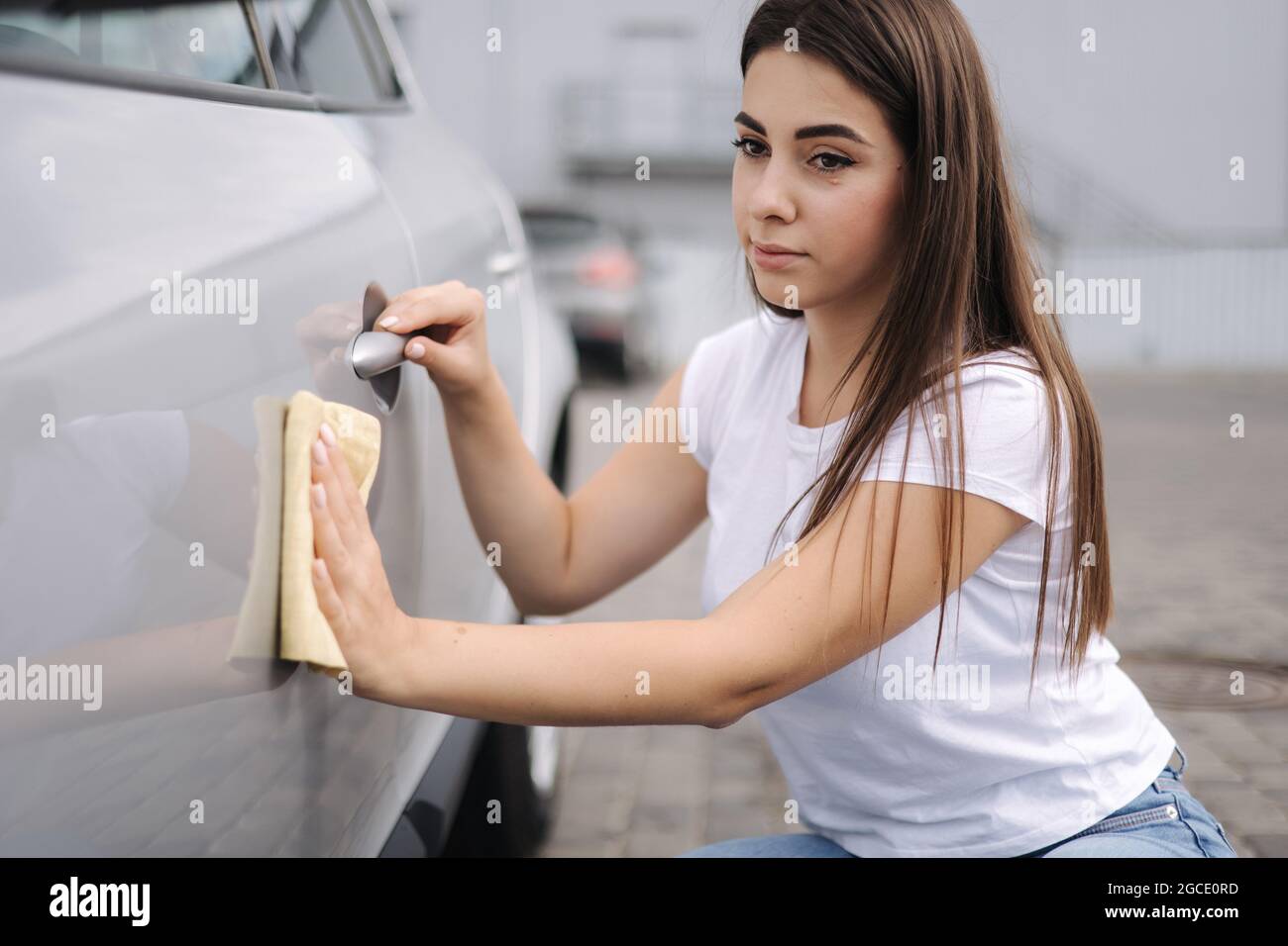 Front view of attractive happy joyful female driver washing her car ...