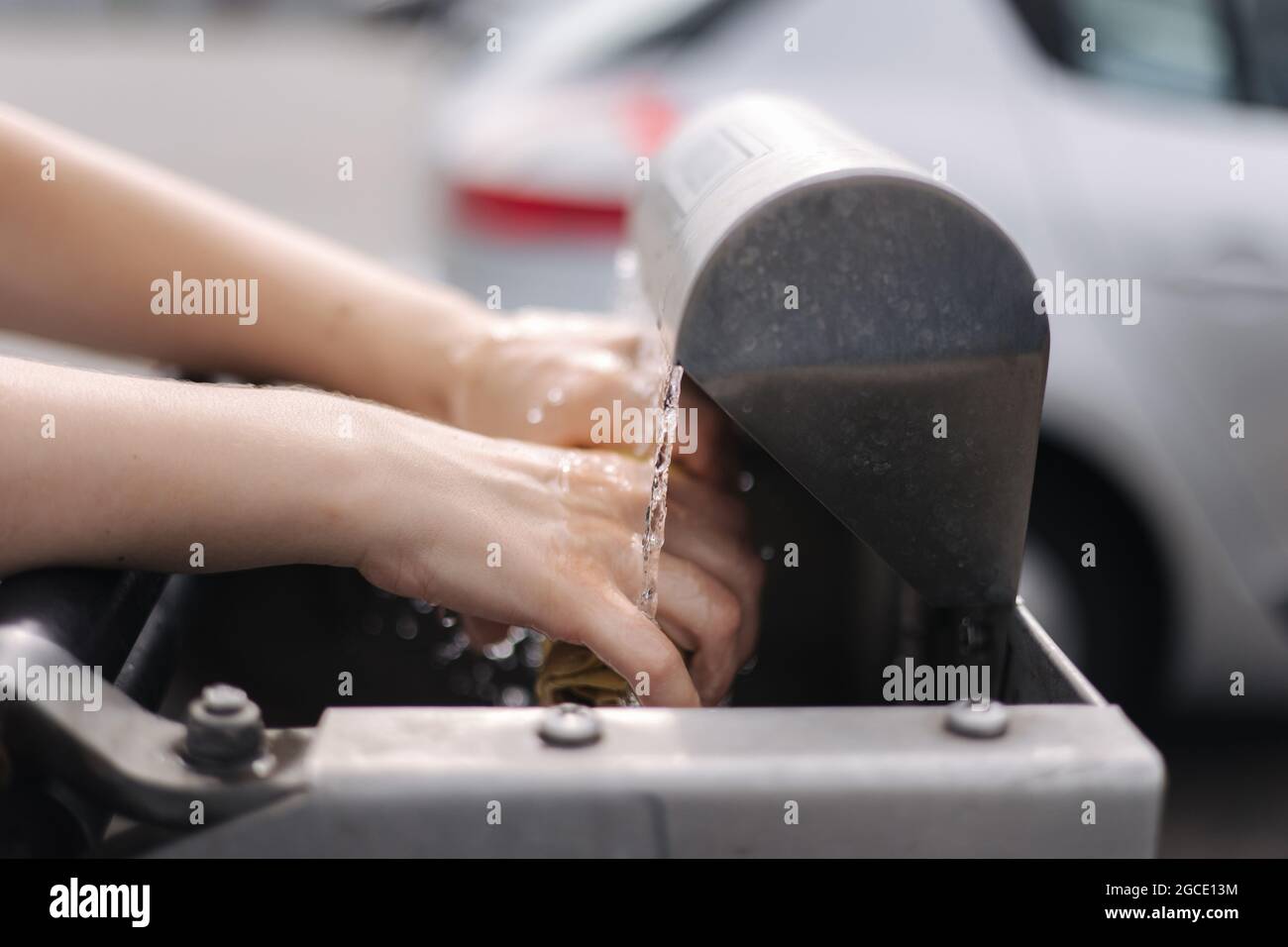 Female wash rug in water. Close-up woman's hand in front of car on sel ...