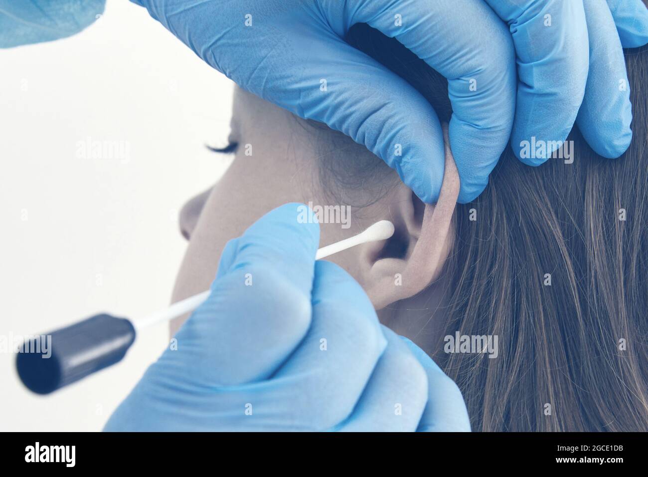 Ear check with cotton bud in medical laboratory, blue toning Stock ...