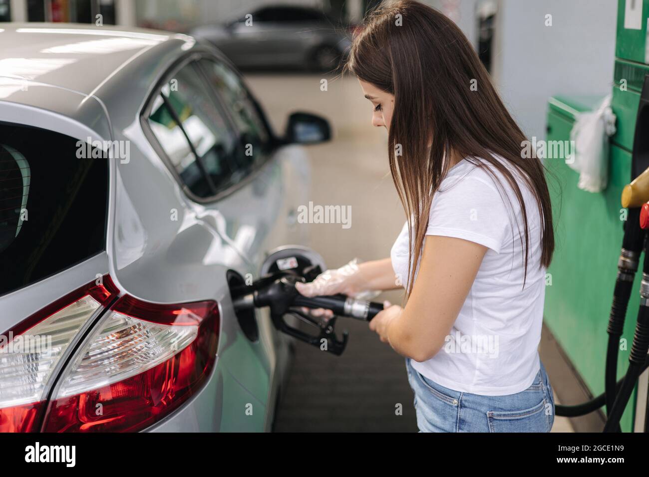 Attractive young woman refueling car at gas station. Female filling ...