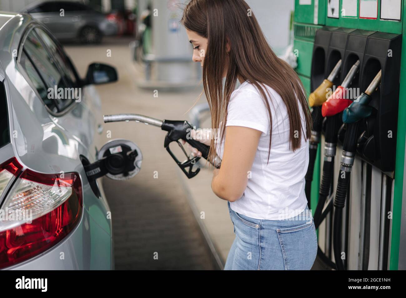 Attractive young woman refueling car at gas station. Female filling ...