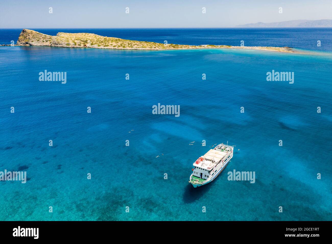 Aerial view of swimmers and snorkelers around a boat in a crystal clear ...