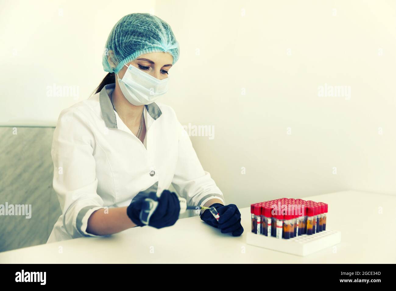lab technician with tube of blood sample and rack with other samples ...