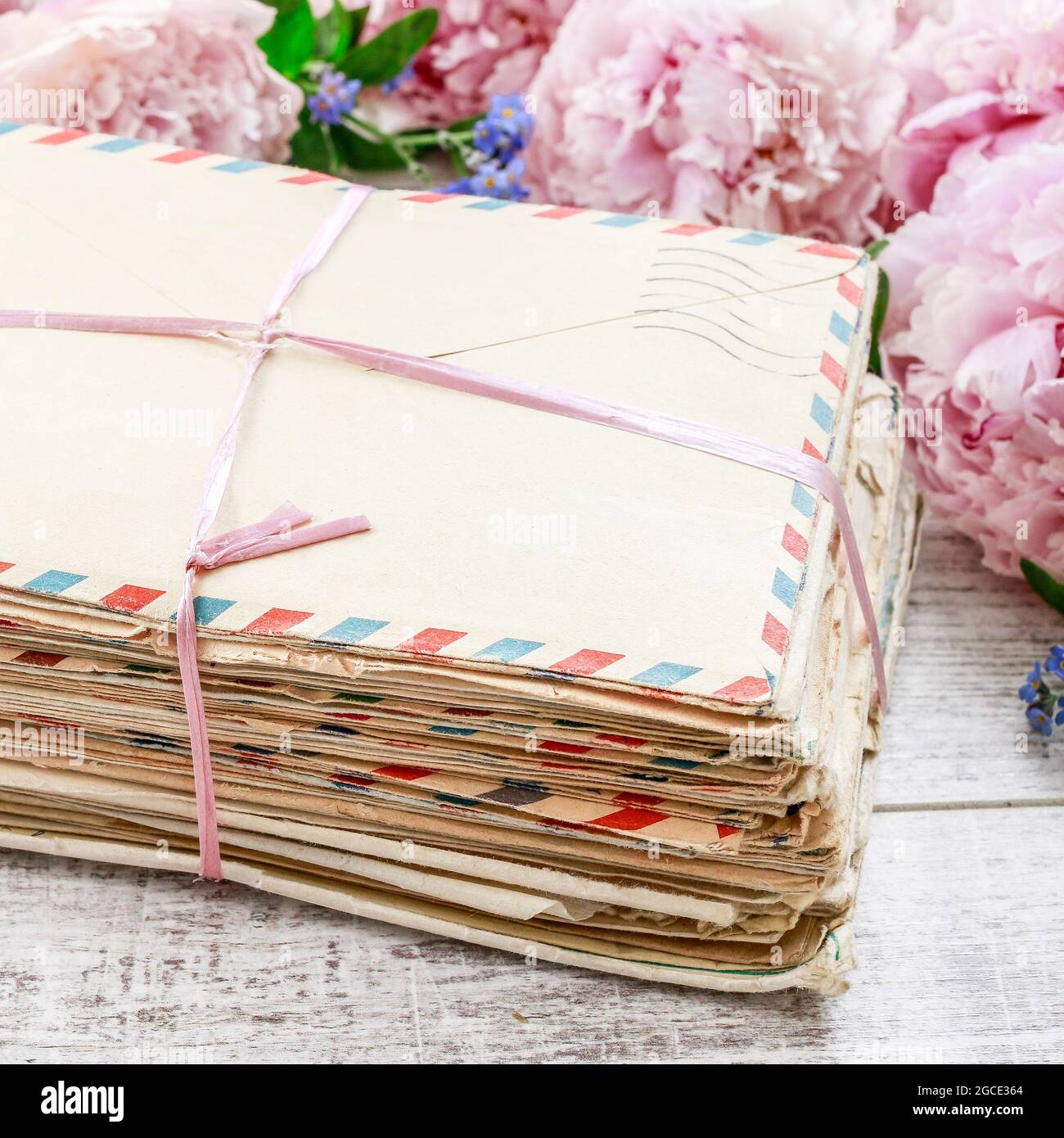 Stack of vintage love letters and pink peonies in the background. Retro ...