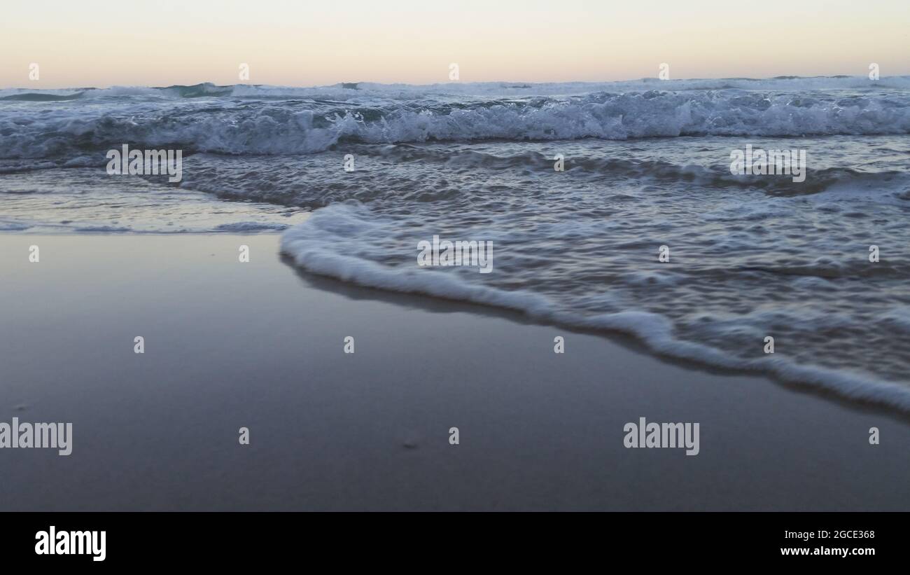 Close up of waves at the shoreline at sunset Stock Photo - Alamy