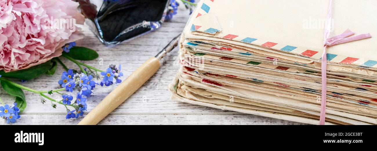 Stack of vintage love letters and pink peonies in the background. Retro ...