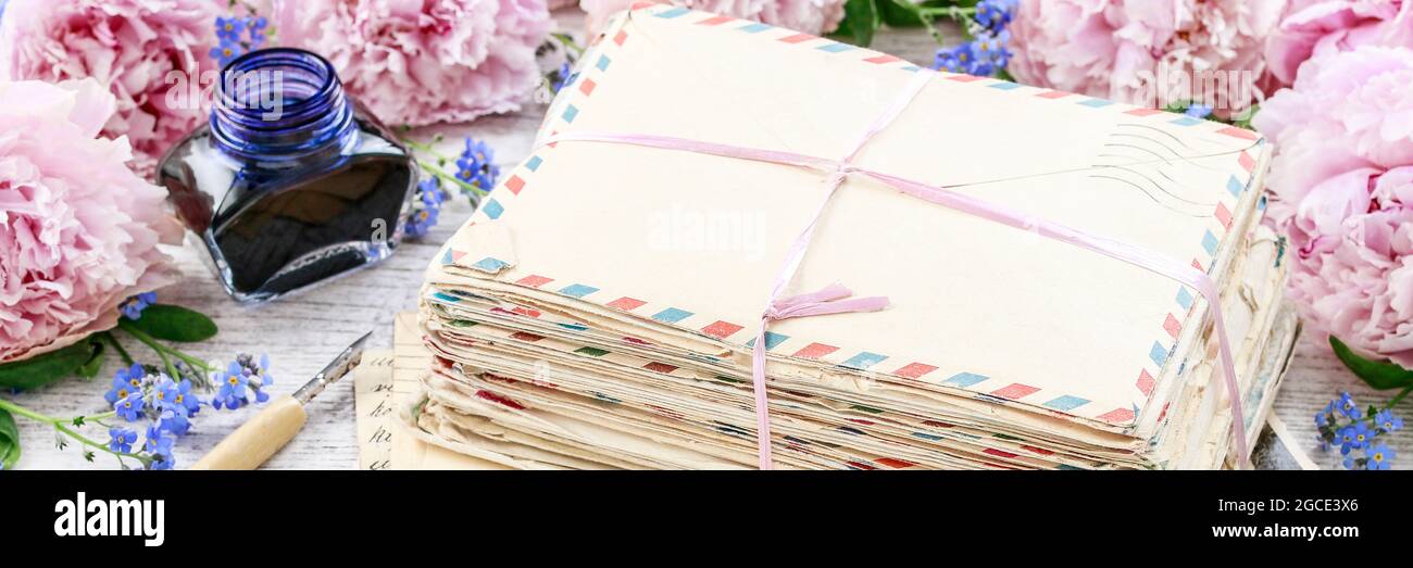 Stack of vintage love letters and pink peonies in the background. Retro ...