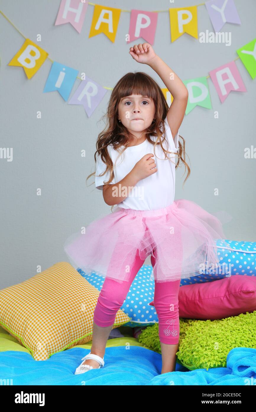 Little girl dancing on bed in room on grey wall background Stock Photo ...