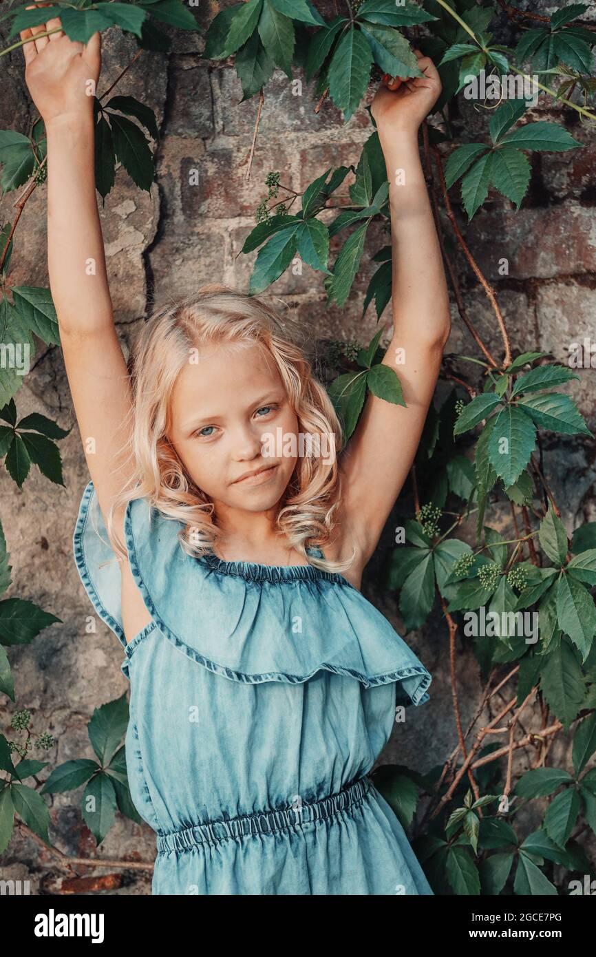 blonde with curly hair raised her hands up against the wall with wild ...
