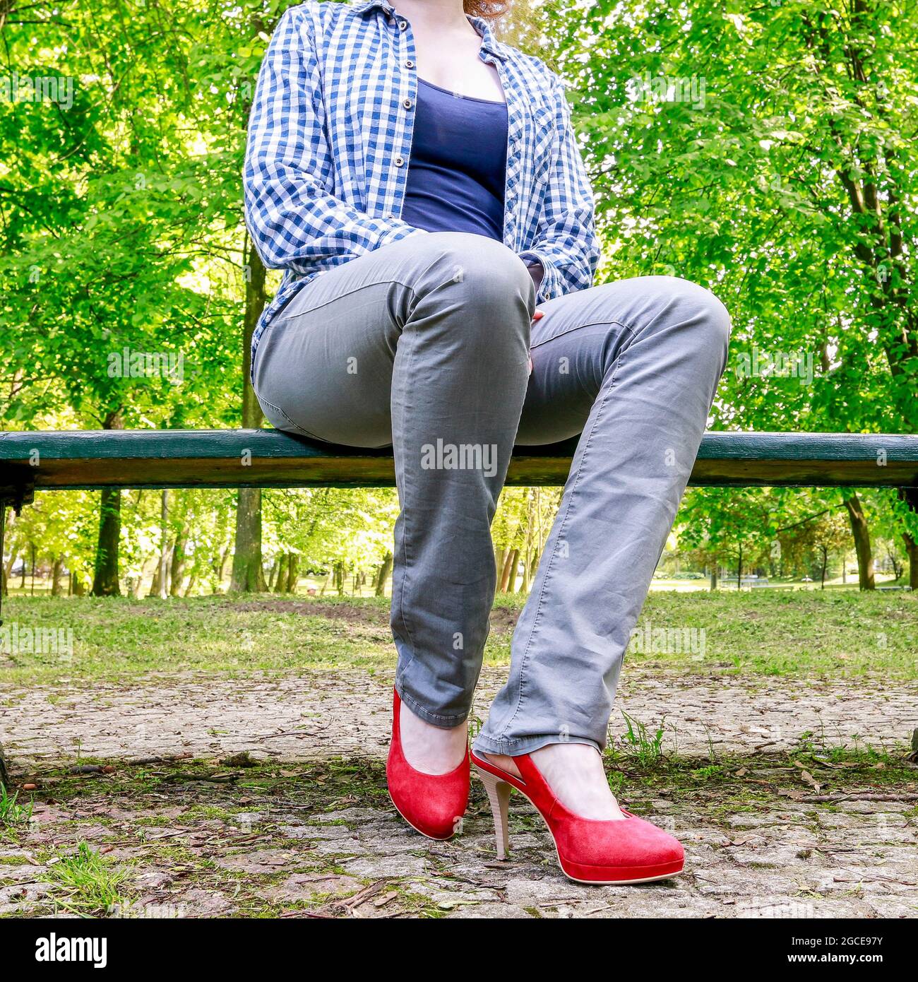 Young woman wearing red slingback shoes sitting on the bench in ...
