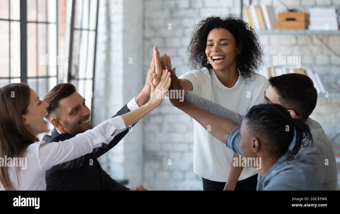 Smiling diverse employees give high five at workplace Stock Photo - Alamy