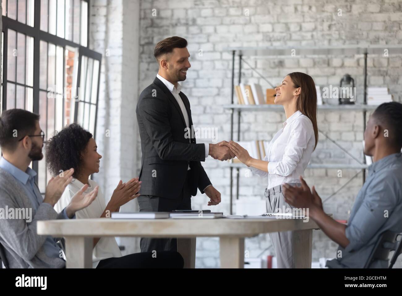 Smiling male boss handshake excited female colleague Stock Photo - Alamy