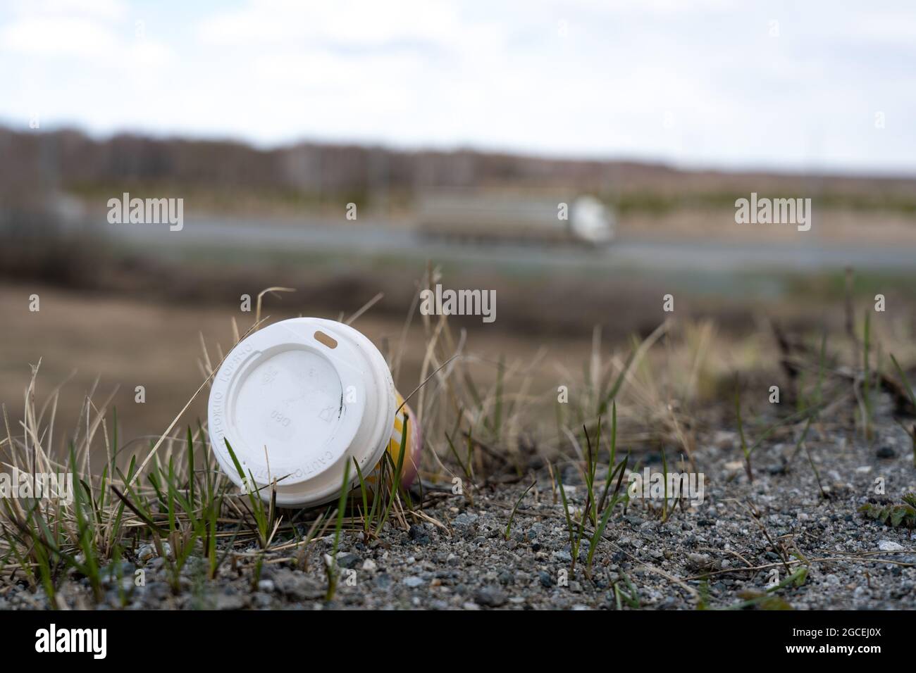 Plastic waste on the side of the road in the grass. Used coffee cup ...