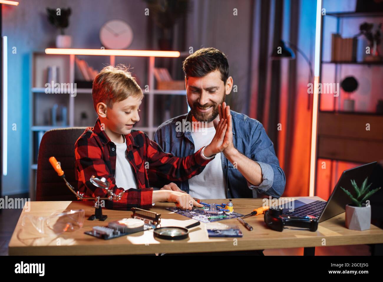 Happy little boy giving high five to his father after successful ...