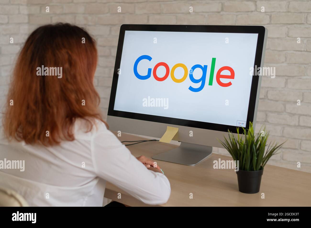 A woman sits at a computer with a google logo on the monitor Stock ...