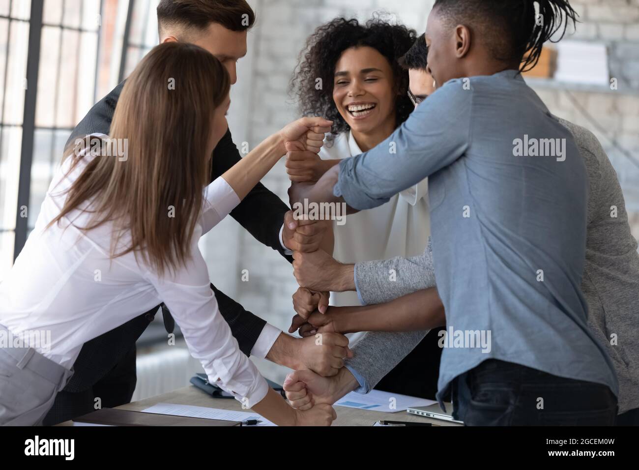 Excited diverse employees stack hands in office Stock Photo - Alamy
