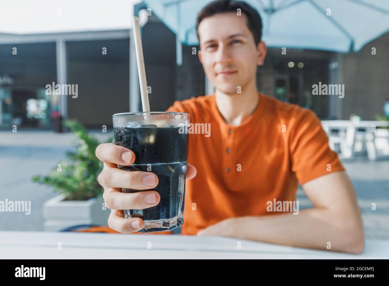 Man drinks unusual sparkling water in black color with ice and lemon ...