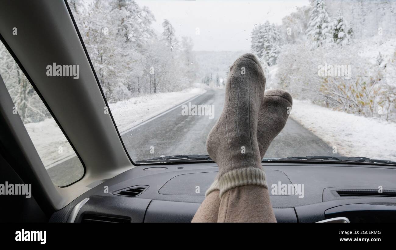Female feet in woolen socks on the dashboard of a car in winter ...