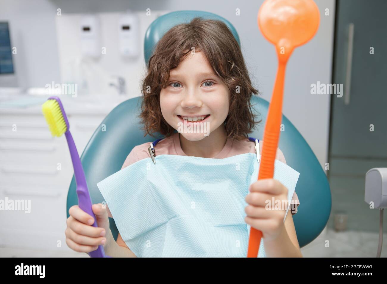 Excited young boy smiling to the camera, holding big dental mirror and ...