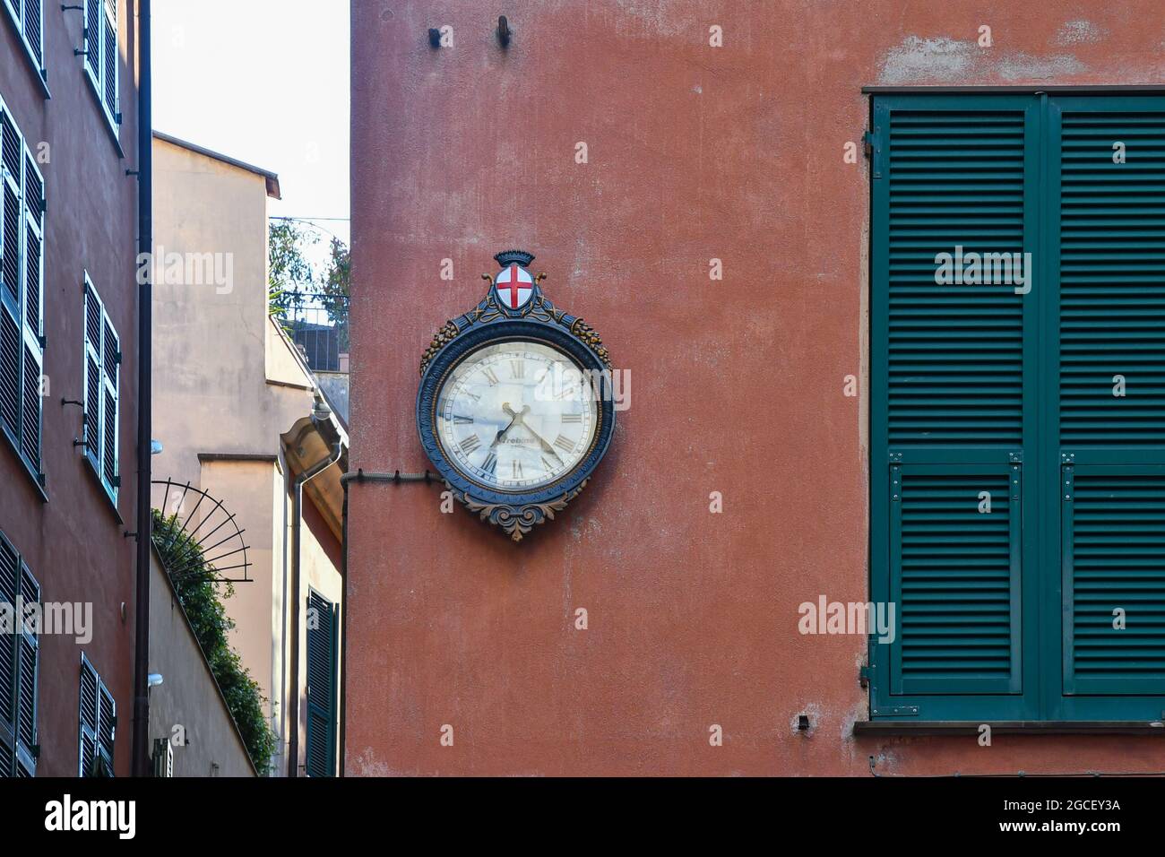 An ancient street wall clock decorated with the city coat of arms on ...