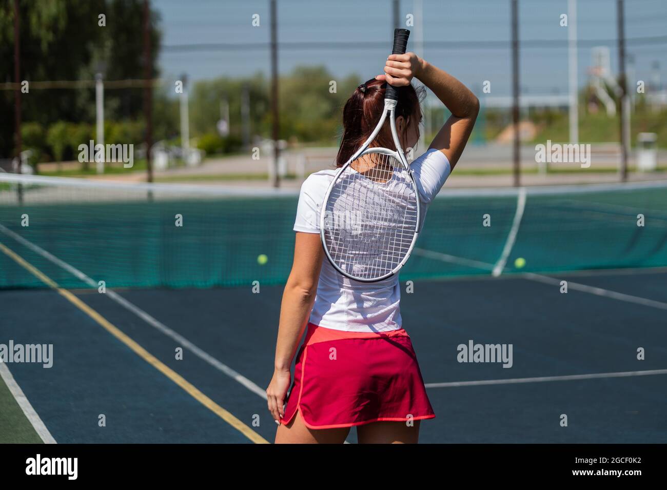 Woman in skirt standing back on the tennis court and holds the racket ...