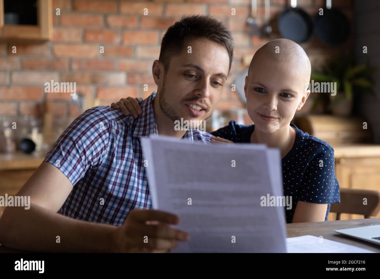 Happy wife with cancer and husband doing routine domestic paperwork ...