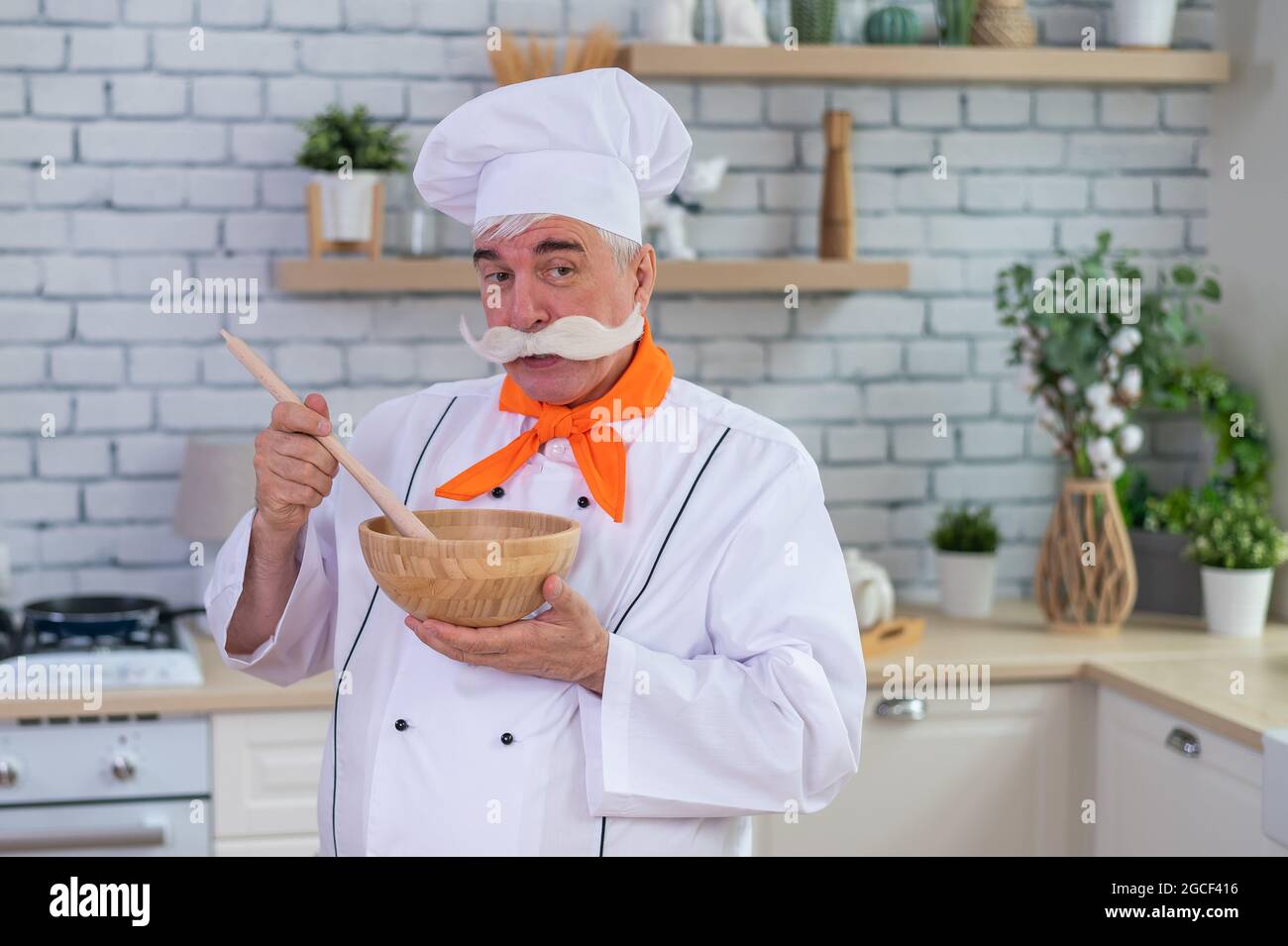 An old man with a bushy gray mustache in a chef's hat is cooking in the ...