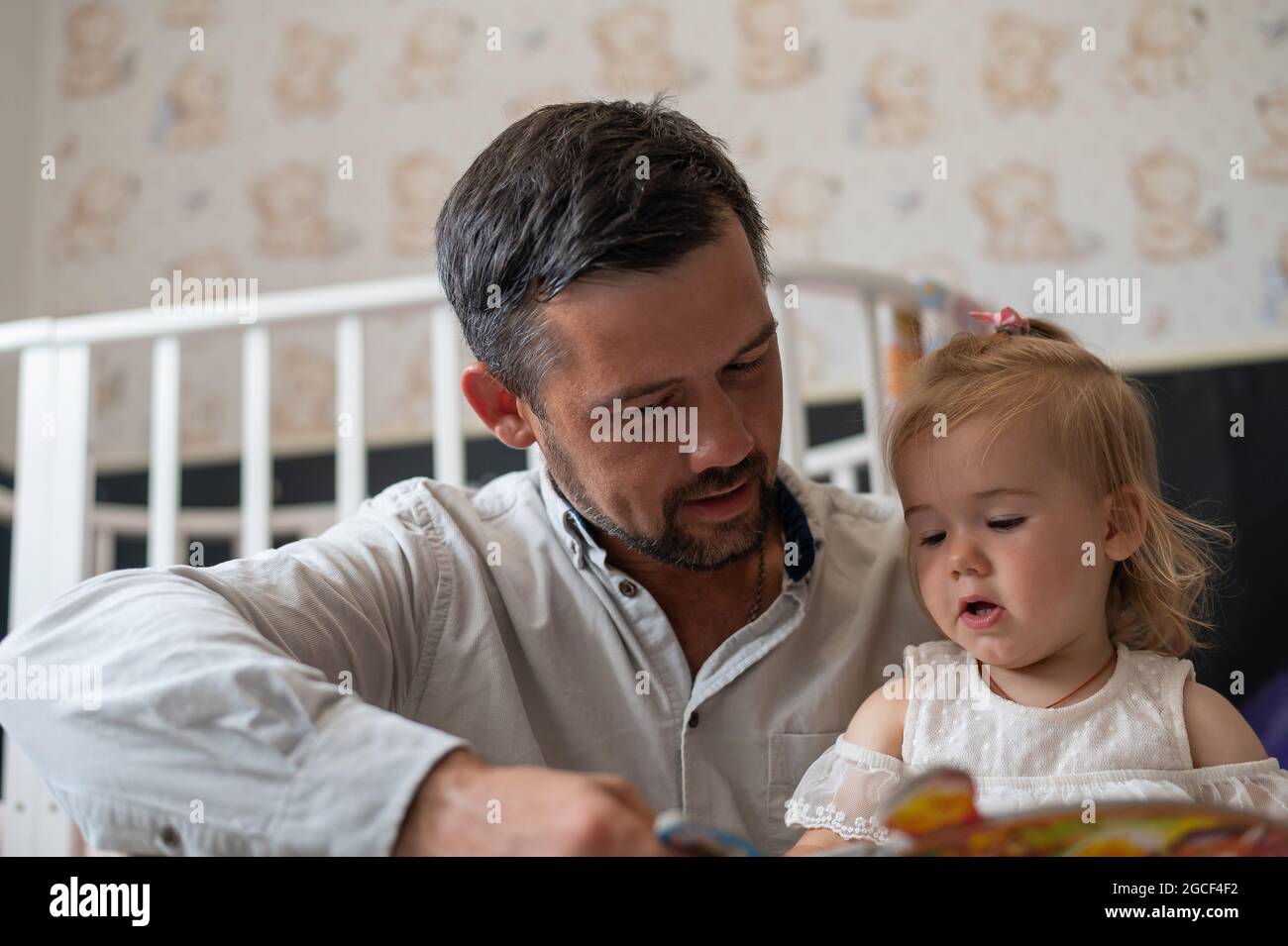 A caring father reads a fairy tale to his little daughter in the ...