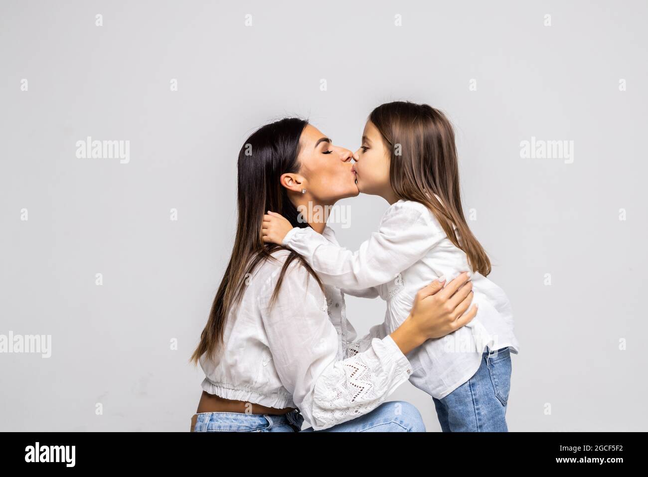 Portrait of little daughter kissing her beautiful happy mother ...