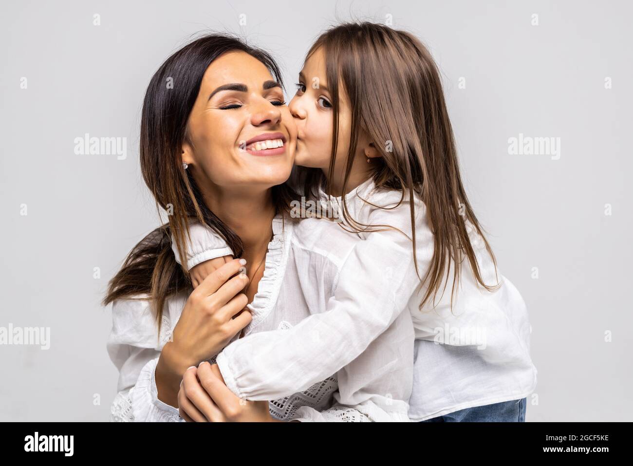 Portrait of daughter kissing her mother on white background Stock Photo ...