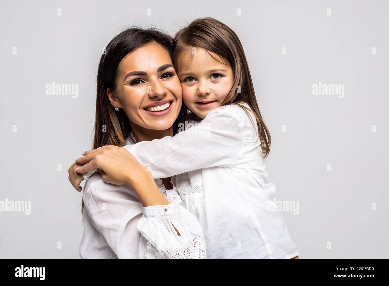 Happy beautiful young mother hug her little cheerful daughter on white background Stock Photo ...