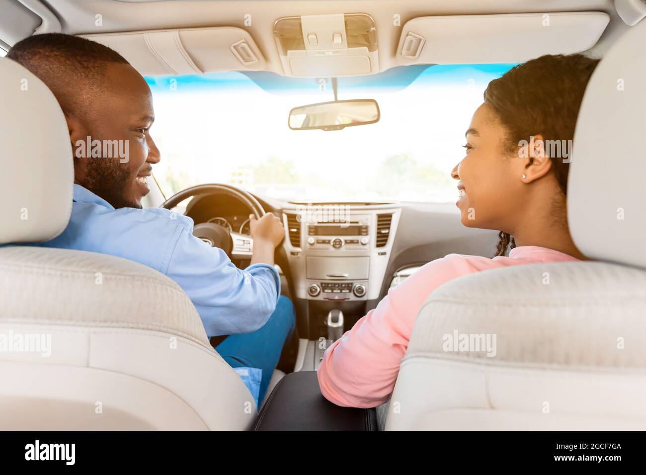 Rear back view of smiling handsome African American man driving modern ...