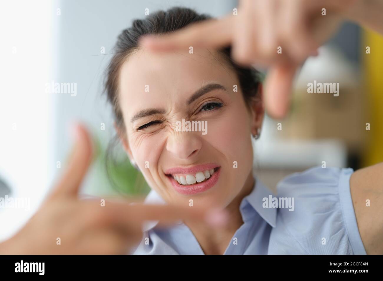 Young woman winks and makes a gesture with hands to photo frame Stock ...