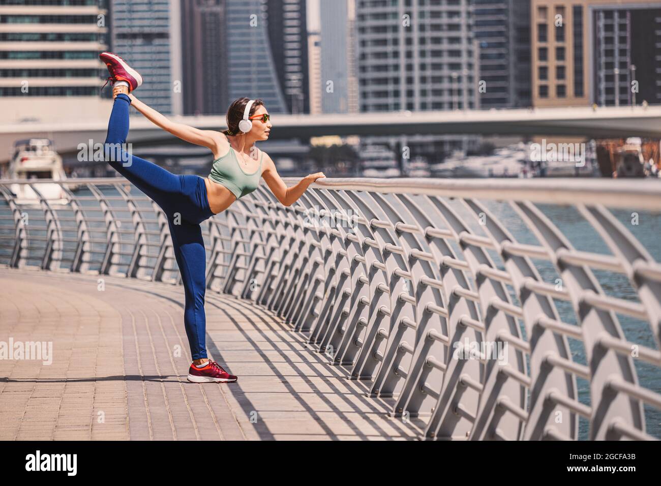 Fit woman stretches in a yoga pose or dance on the city embankment ...