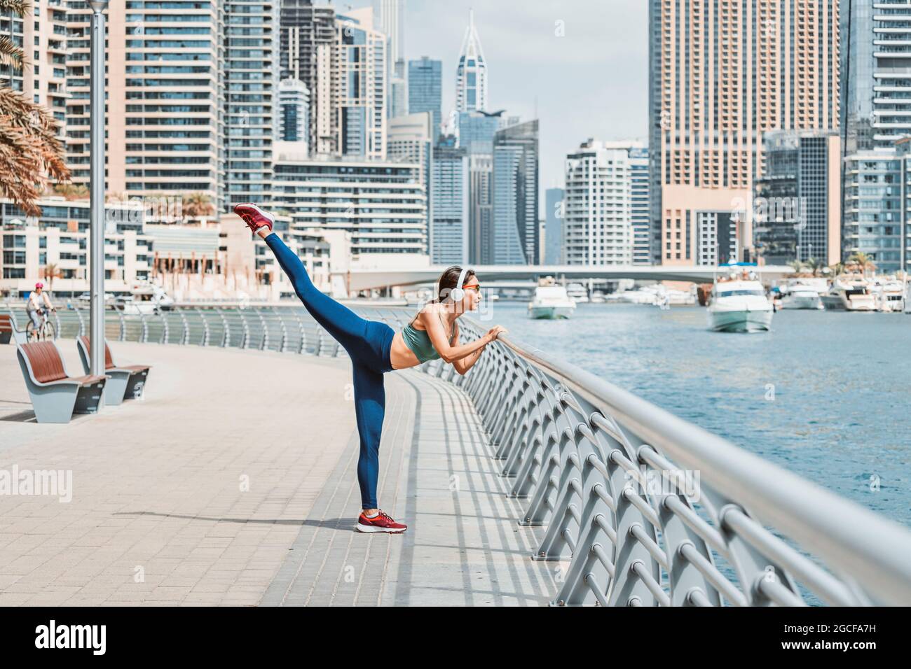 Fit woman stretches in a yoga pose or dance on the city embankment ...