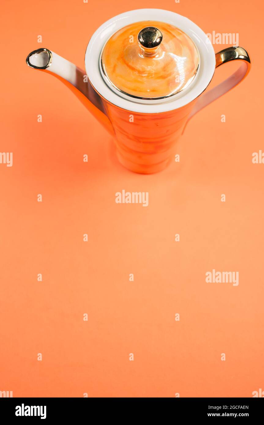 A close up of an orange covered ceramic teapot on an orange isolated ...
