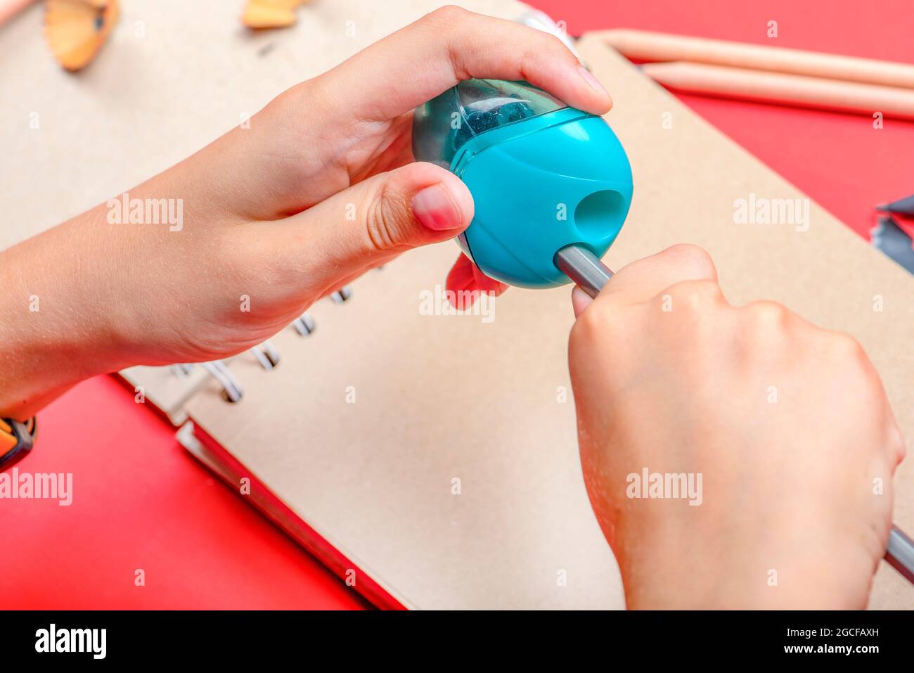 Sharpen pencils. The child's hands sharpen a pencil at school in the lesson. In the background ...