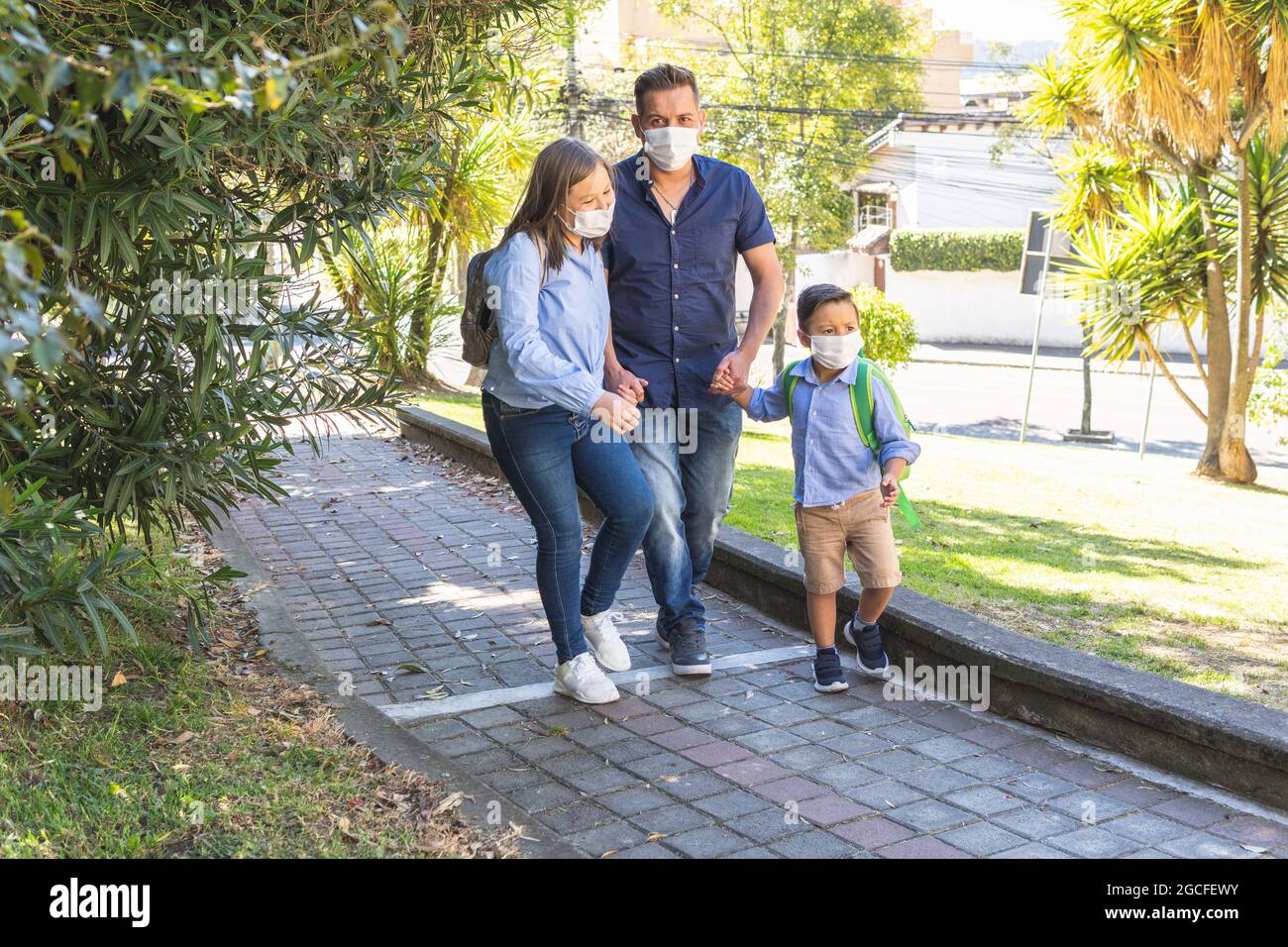 A father with his son and daughter wearing masks on the way to school ...