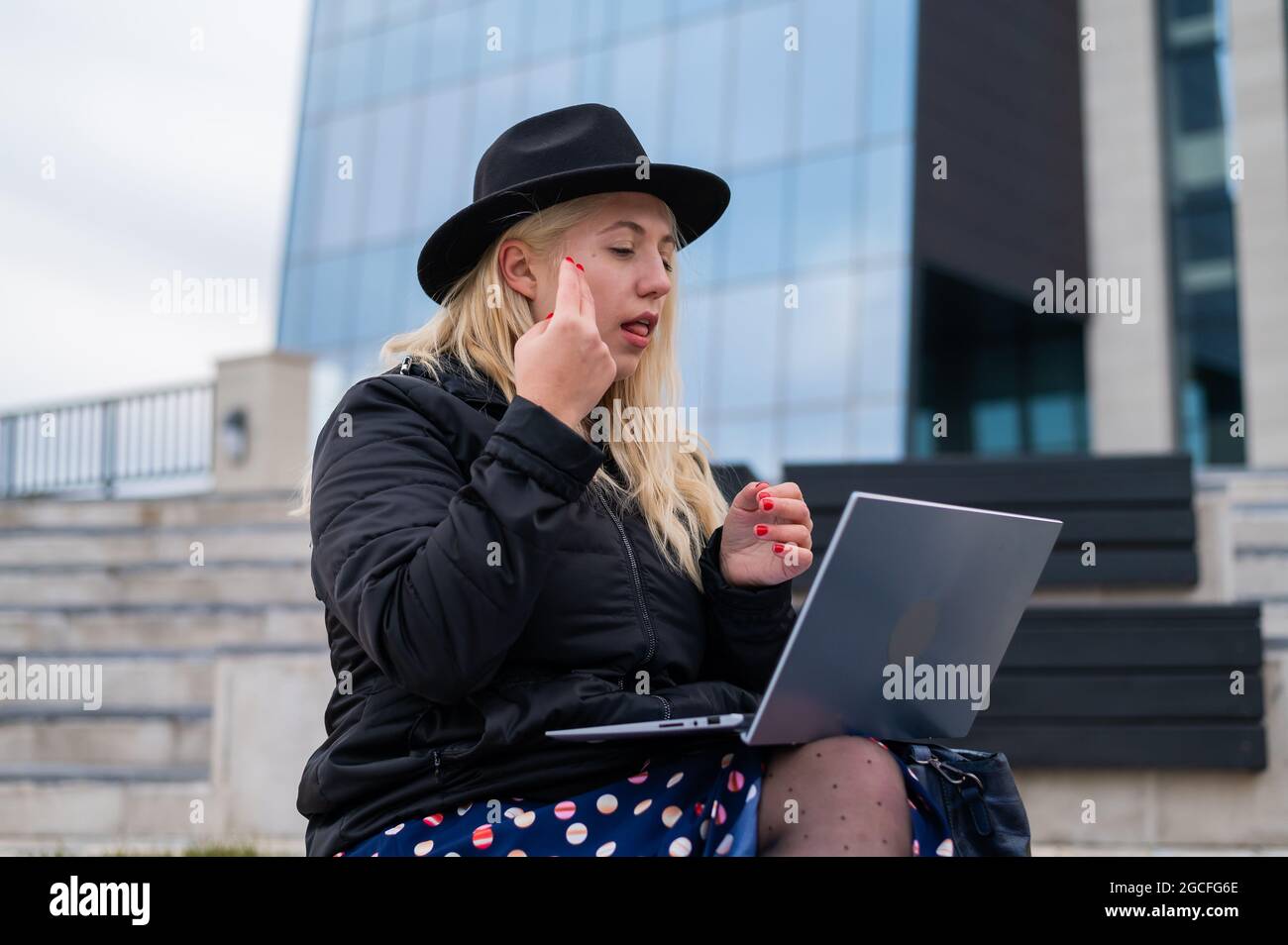 Young woman speaks sign language on a video call on a laptop outdoors ...