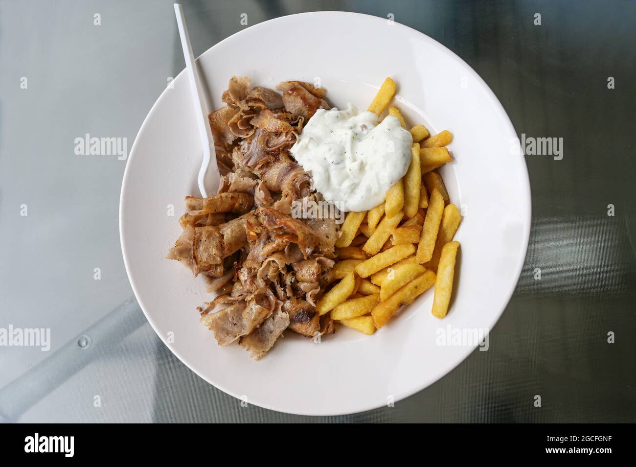 Doner kebab meat slices from rotating roasting spit with french fries ...