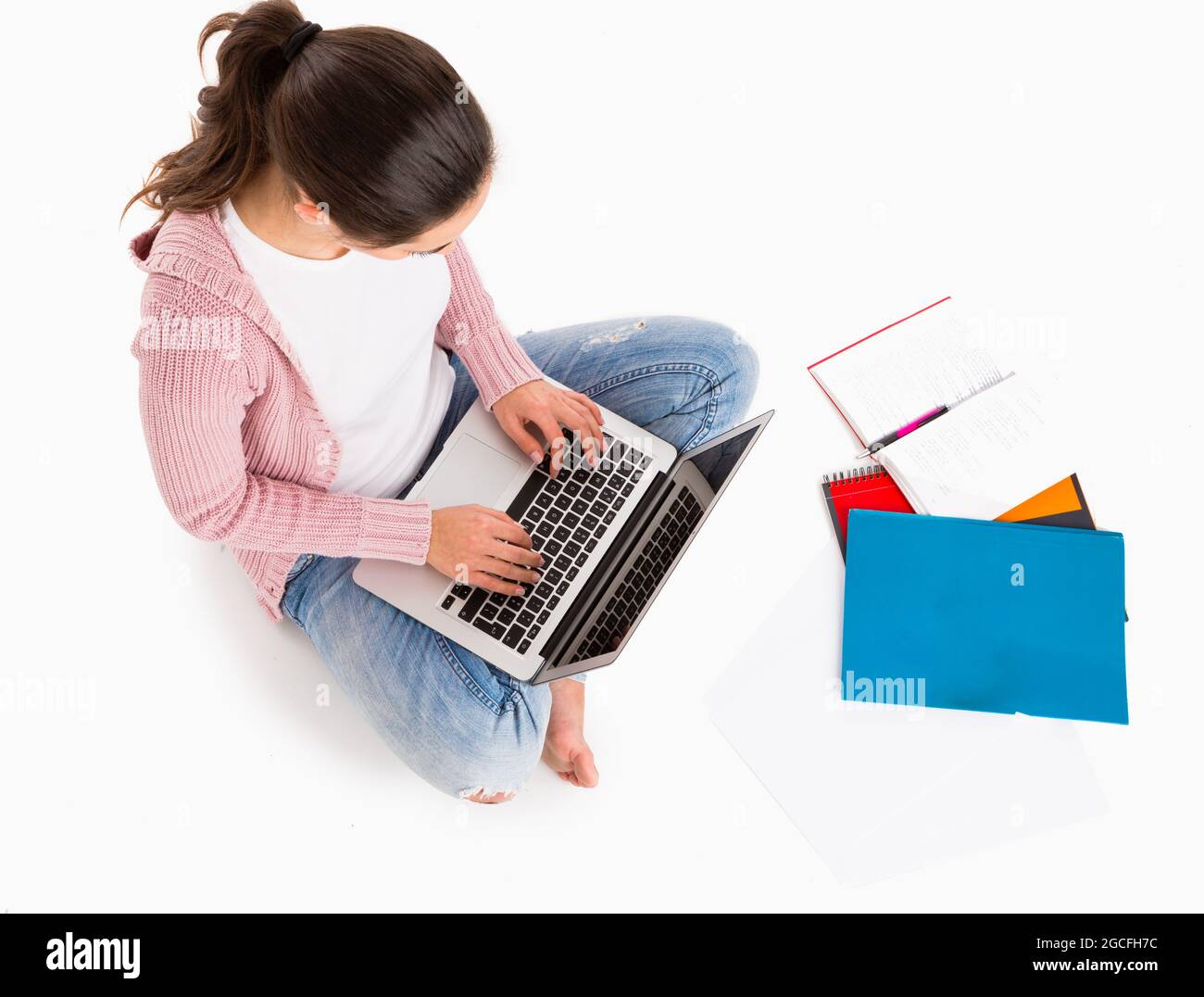 Young female student sitting with crossed legs working with a laptop ...
